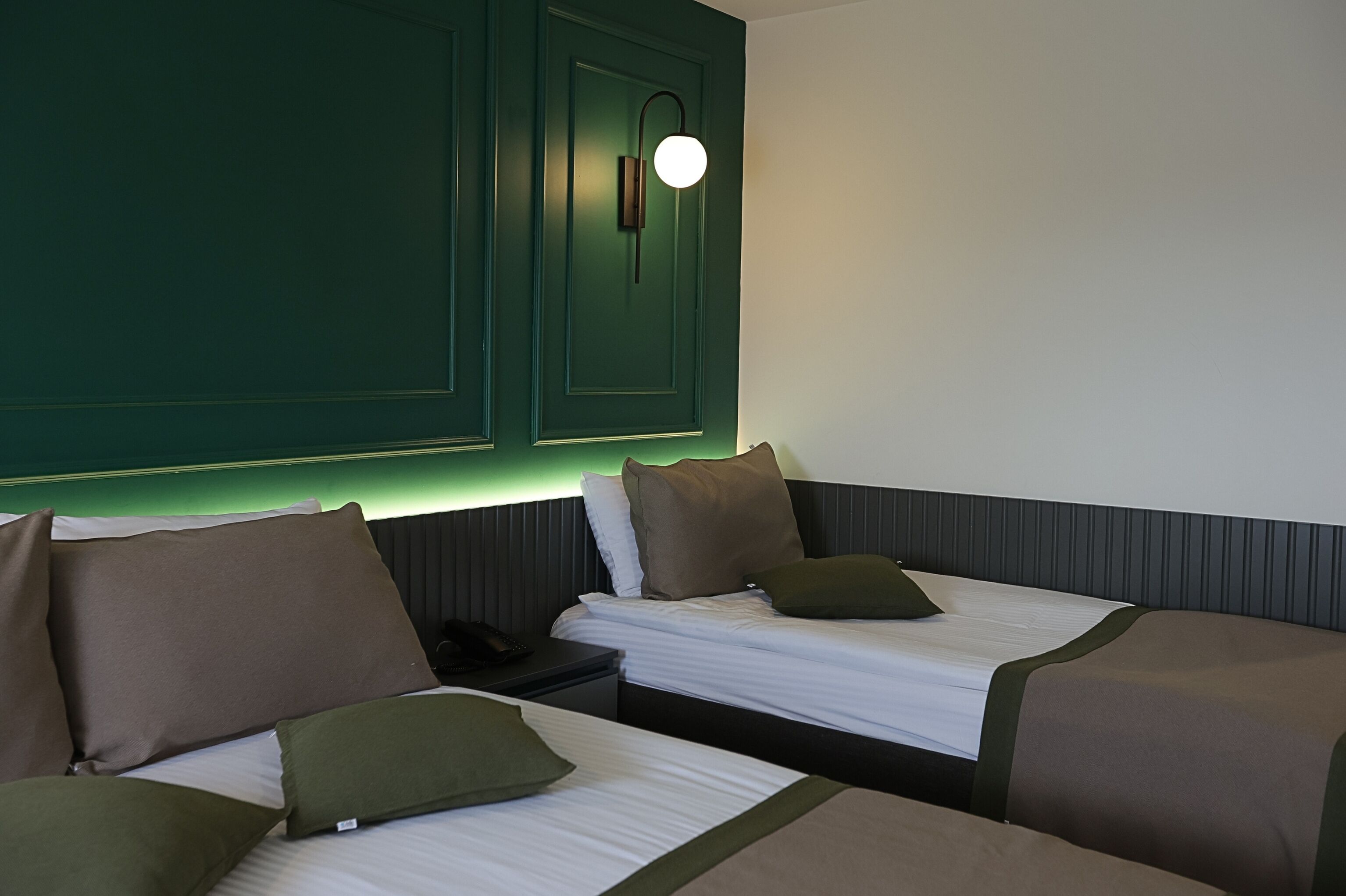 Quarto de hotel com duas camas, cada uma com travesseiro e mesa de cabeceira.