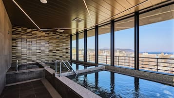 Uma piscina infinita interior com vista para a cidade, uma parede de madeira ripada e um design de teto moderno.