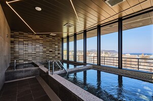 Uma piscina infinita interior com vista para a cidade, uma parede de madeira ripada e um design de teto moderno.