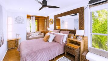 Quarto com cama, mesa de cabeceira, abajur e ventilador de teto.