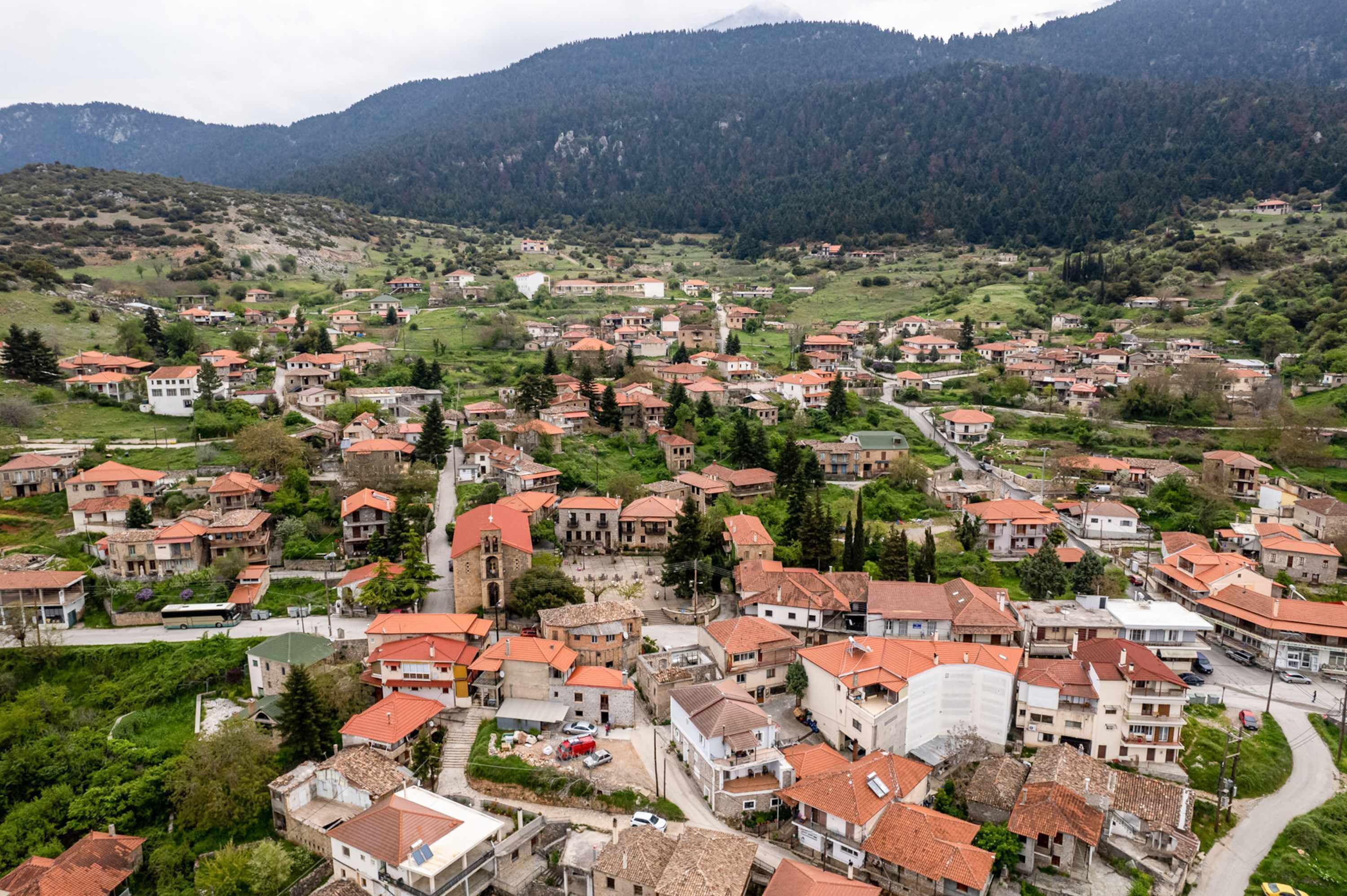 Uma cidade com edifícios de telhados vermelhos, uma igreja no centro e uma montanha ao fundo.