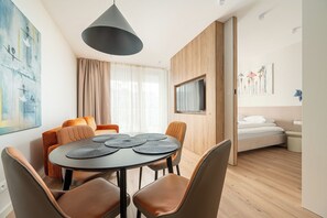 Uma sala de estar moderna com área de jantar, televisão de tela plana na parede e uma janela grande com cortinas.