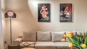 Uma sala de estar com sofá, luminária, um vaso com tulipas e dois quadros na parede.