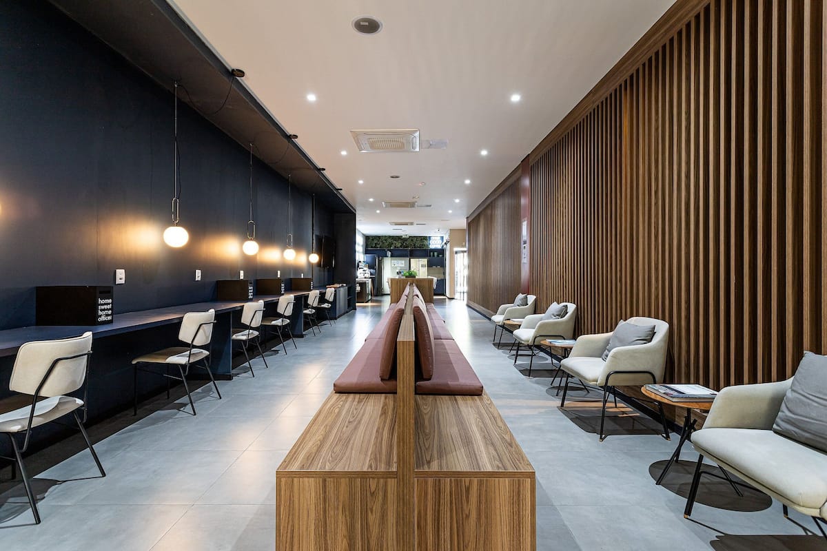 Um lobby moderno com balcão de recepção, área de estar e parede de madeira.