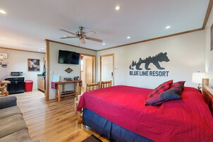 Quarto com uma cama grande, um ventilador de teto, uma TV e uma placa na parede com a inscrição 'Blue Line Resort'.