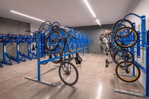Uma área de estacionamento para bicicletas com vários suportes azuis e bicicletas.