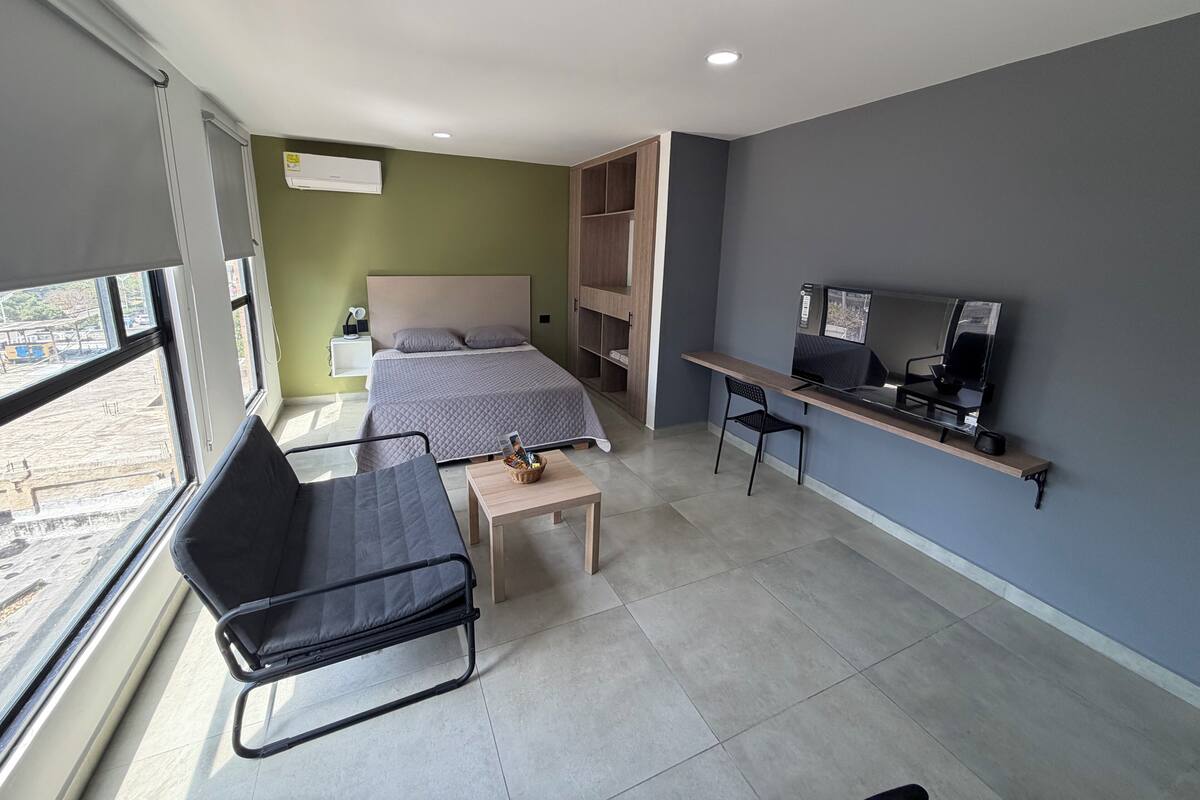 Quarto moderno com cama, escrivaninha, cadeira e janela.