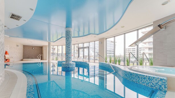 Uma piscina interior com água azul cristalina, piso azulejado e design moderno.