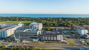 Uma área urbana moderna com edifícios altos, um estacionamento e vista para o mar.