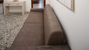 Uma sala de estar moderna com um sofá, uma TV de tela plana, uma escrivaninha e arte abstrata na parede.