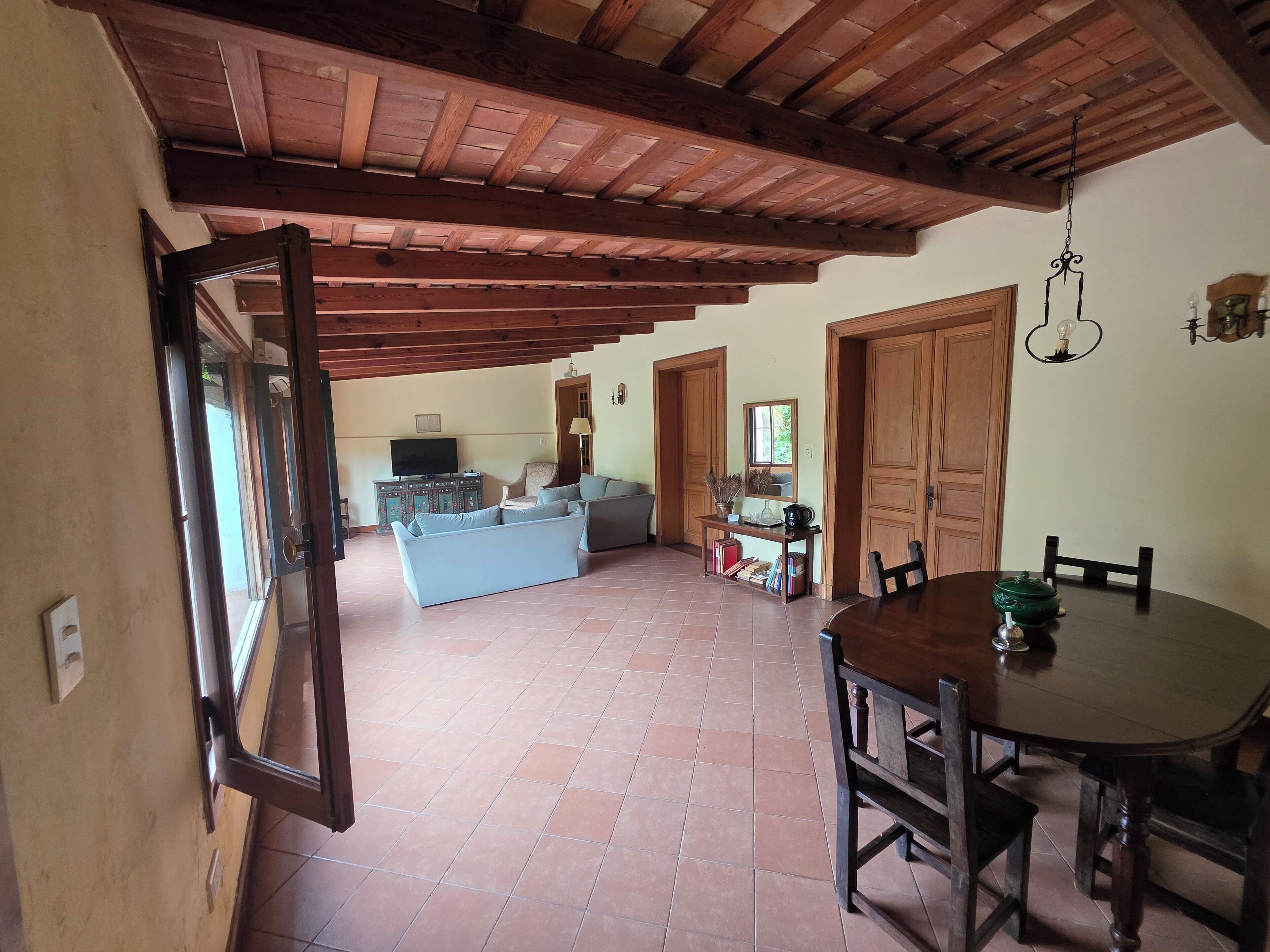 Uma sala de estar ampla com teto de madeira, uma mesa de jantar e um sofá.