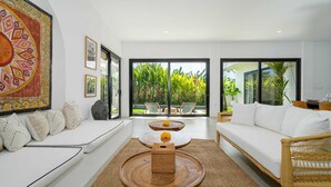 Uma sala de estar moderna com um sofá branco, uma poltrona de vime e uma mesa de centro com cesta trançada.