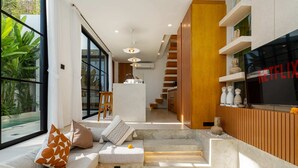 Uma sala de estar moderna com sofá, televisão e escada que dá para a cozinha.