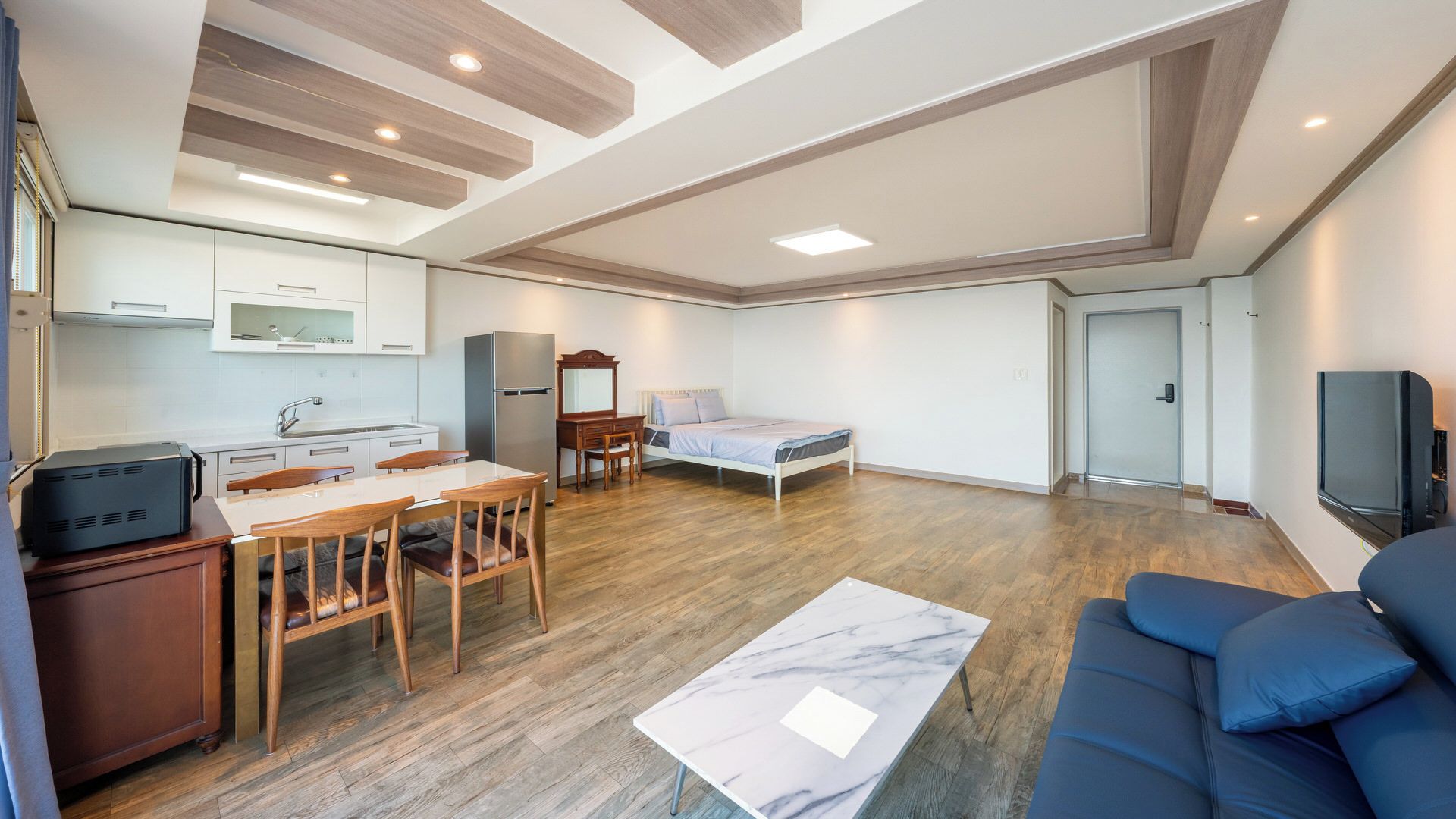 Espaço compacto com cozinha, área de refeições e um quarto.