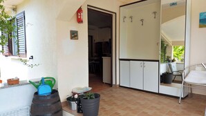 Quarto com um guarda-roupa espaçoso, uma mesinha e uma cadeira. Janela com vista para o verde lá fora.