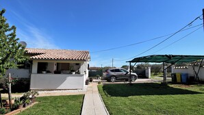 Um imóvel residencial com telhado telhado, calçada pavimentada, gramado verde e um carro estacionado na entrada.
