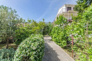 Um caminho ladeado por vegetação exuberante e um edifício com varandas.