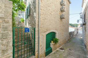 Um edifício de pedra estreito com um portão verde e uma placa indicando que é um apartamento.
