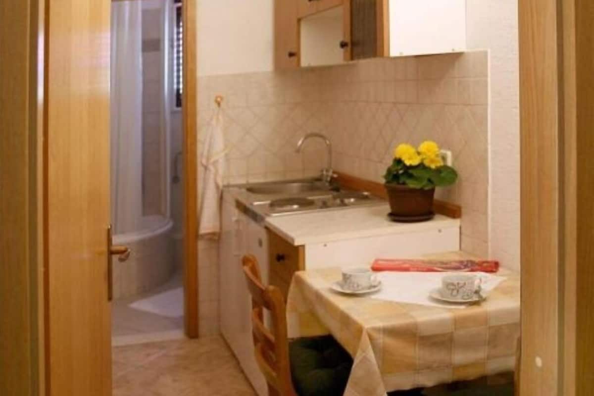 Cozinha compacta com pia, mesa de jantar com cadeiras e uma pequena janela.