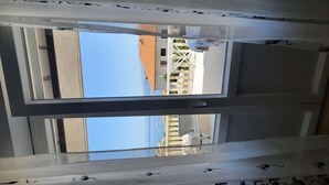 Janela com vista para um edifício com varandas e céu claro.