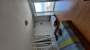 Um quarto com cama, janela e vista do céu.