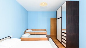 Quarto com duas camas, um guarda-roupa e uma porta.