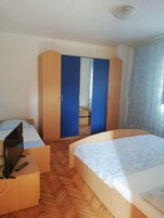 Quarto com duas camas, um guarda-roupa de madeira e uma escrivaninha com um laptop.