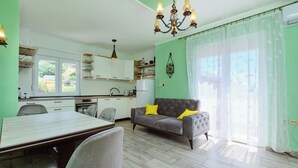 Ampla sala de estar com mesa de jantar, sofá e cozinha ao fundo.