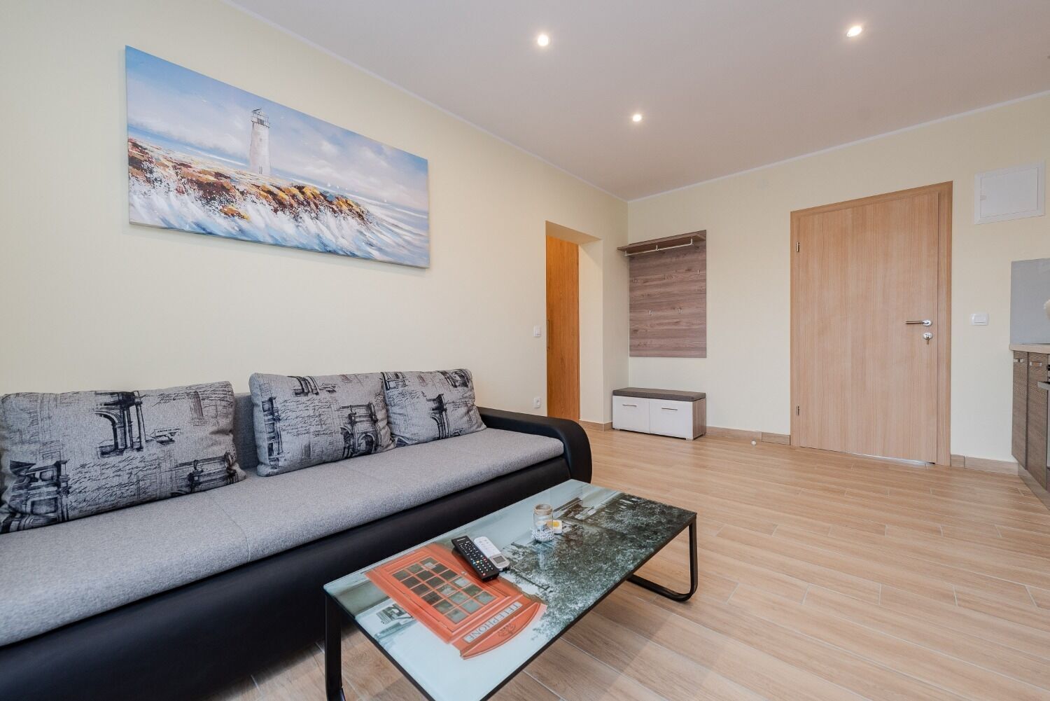 Uma sala de estar moderna com sofá, mesa de centro, pintura, guarda-roupa e porta.