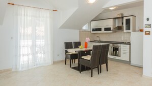 Cozinha moderna com armários brancos, fogão e área de jantar com mesa e cadeiras.
