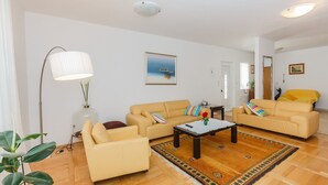 Uma sala de estar com dois sofás bege, uma mesa de centro, um abajur e um quadro na parede.