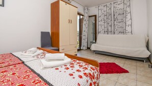 Um quarto com uma cama, um guarda-roupa, uma cadeira e um tapete vermelho.