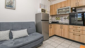 Cozinha compacta com geladeira, micro-ondas, forno e armários de madeira.