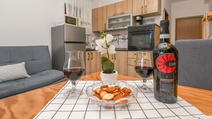 Uma área de refeições com uma mesa posta para dois, incluindo uma tigela de vidro com petiscos, duas taças de vinho e uma garrafa de vinho Bardolino.