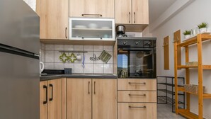 Cozinha moderna com armários de madeira, micro-ondas embutido e geladeira de aço inoxidável.