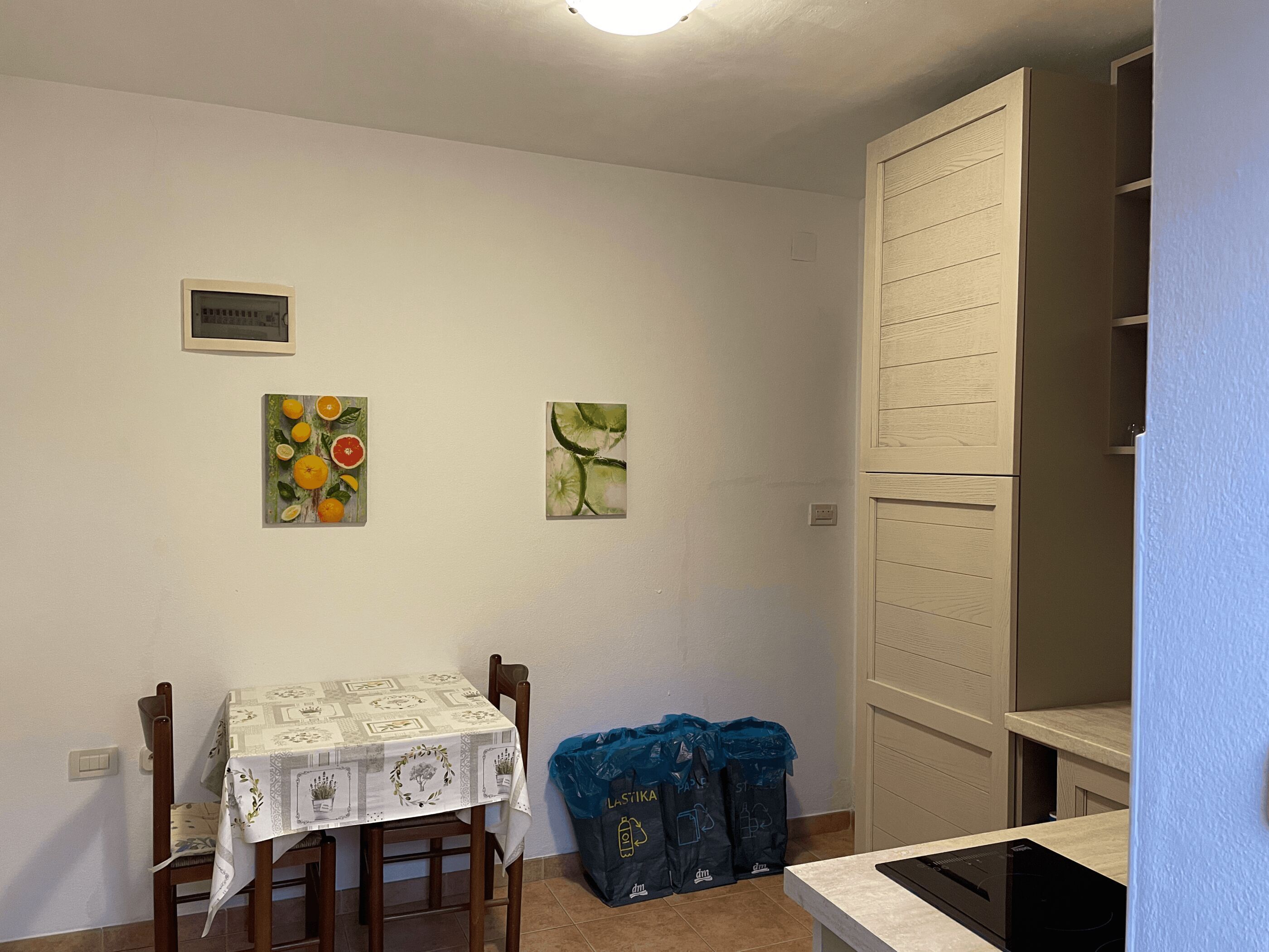 Uma cozinha com mesa, cadeiras e um armário.