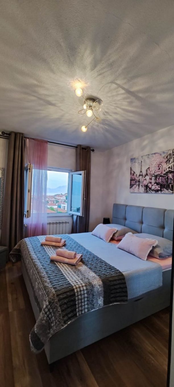 Quarto com uma cama grande, vista da cidade pela janela e luminária no teto.