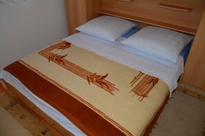 Uma cama com manta estampada, almofadas e cabeceira de madeira.