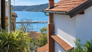 Um edifício costeiro com telhado ladrilhado, chaminé de tijolos e vista para o mar e um cais ao fundo.