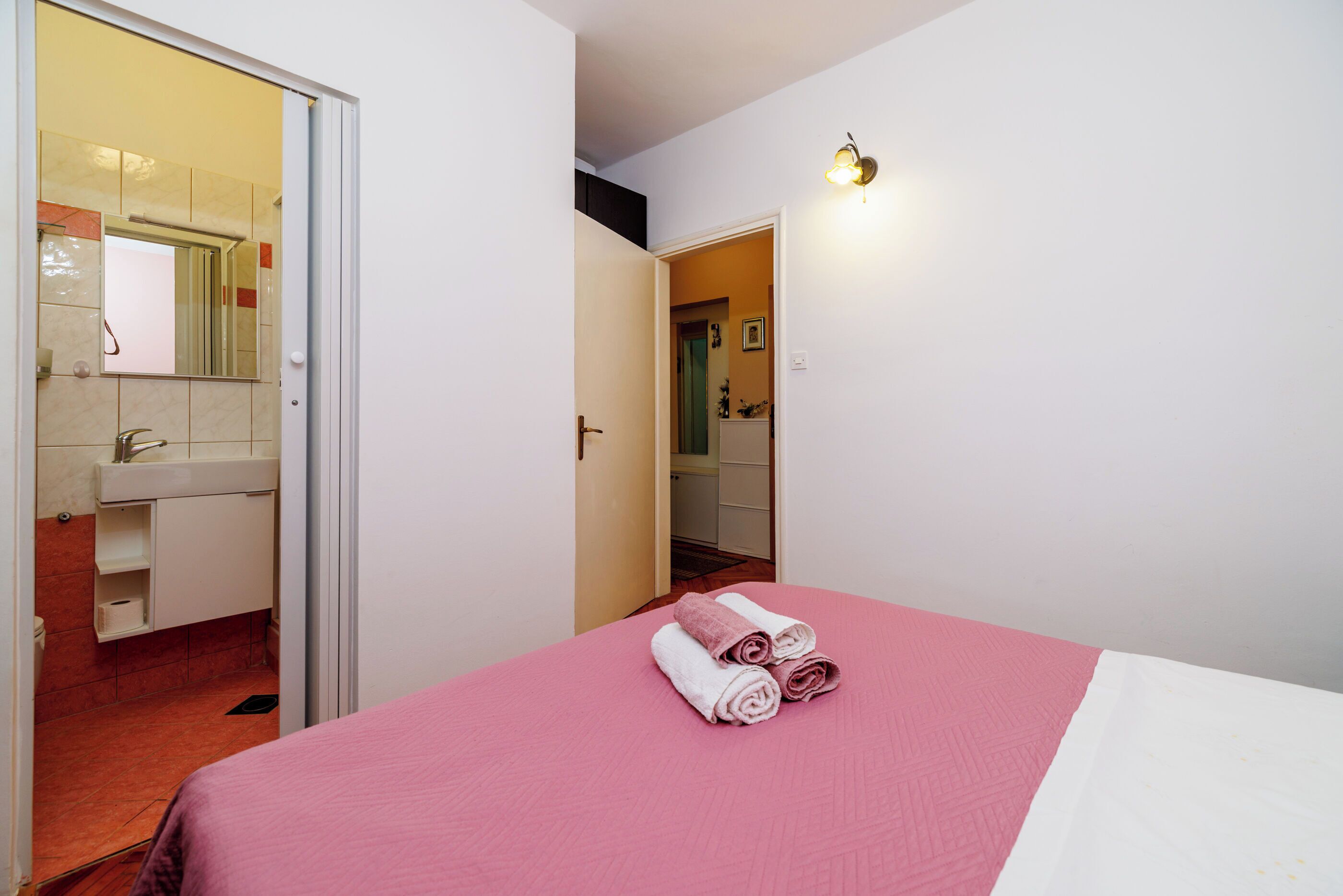 Quarto de hotel com cama, banheiro com pia e espelho.