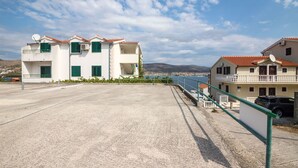 Uma área residencial costeira com edifícios brancos, persianas verdes e vista clara para o mar.