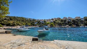 Uma paisagem costeira com barcos atracados em um porto, rodeada por casas e vegetação.