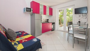 Um espaço compacto com cozinha americana, área de jantar e cama com colcha colorida.