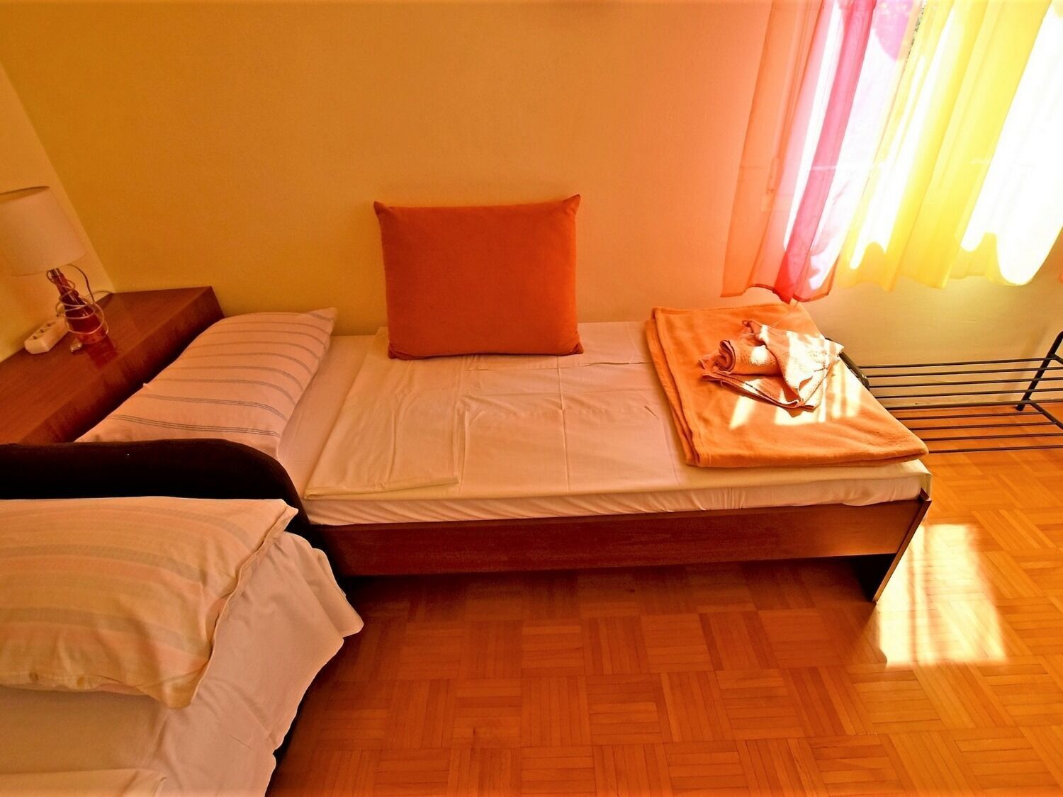 Quarto de hotel com cama, mesa de cabeceira, abajur e janela com cortinas.