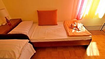 Quarto de hotel com cama, mesa de cabeceira, abajur e janela com cortinas.