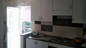 Cozinha compacta com armários brancos, fogão a gás e pia.