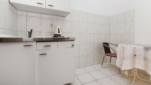 Uma cozinha com armários brancos, uma chaleira e uma mesa com toalha.