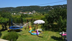 Uma área ao ar livre com gramado, um trampolim, piscina inflável e balanço.