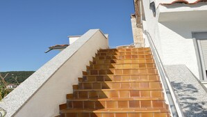 Uma escadaria com uma parede branca e um céu azul claro ao fundo.