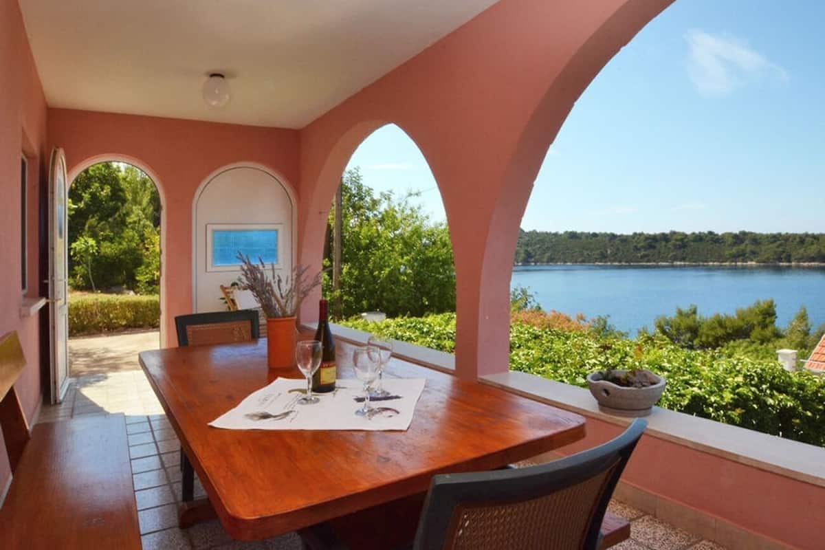 Uma mesa de jantar de madeira com vista para um lago e vegetação.